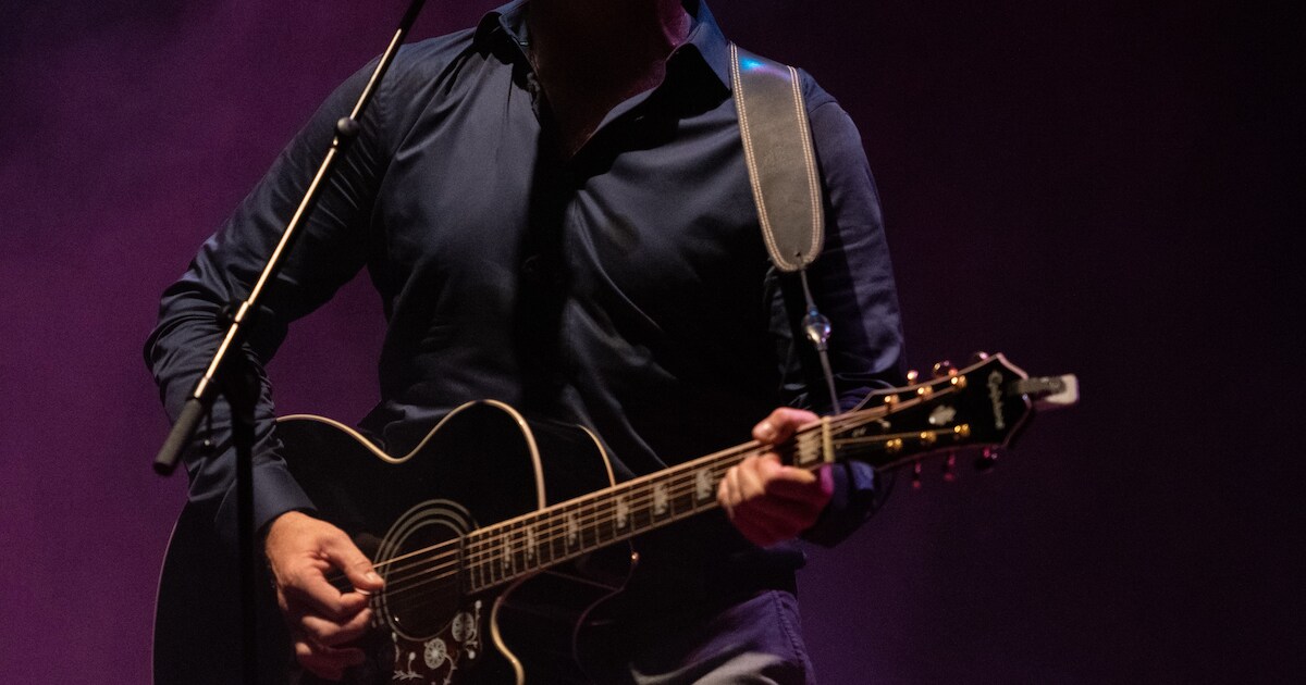 Zingen en spelen net als Neil, inclusief jaren 70-outfit en gitaar ...